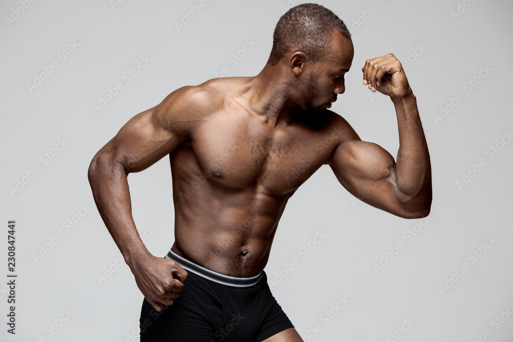 Fit young man with beautiful torso, isolated on gray background. The ...
