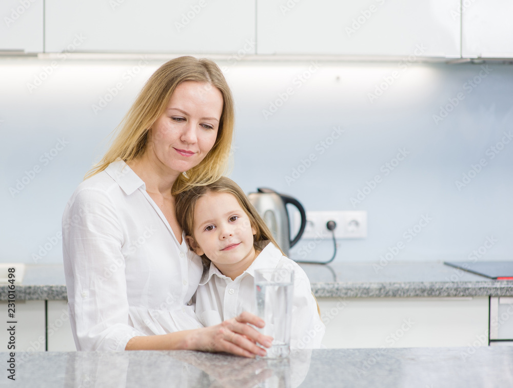 mother with a glass of water hugging her daughter in the kitchen Stock ...
