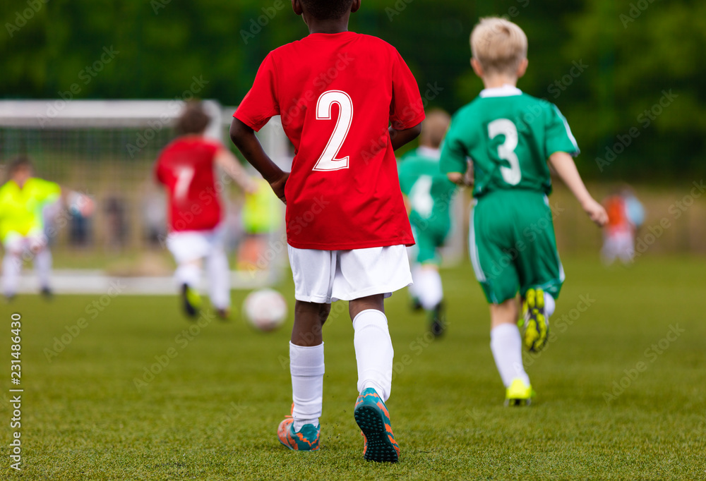 Multiracial kids kicking football on the sports field. An action sport ...