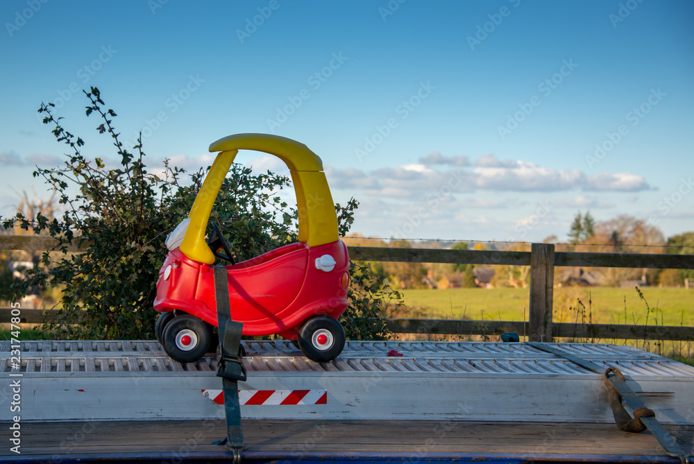 funny picture of small red toy car being delivered on an oversized ...