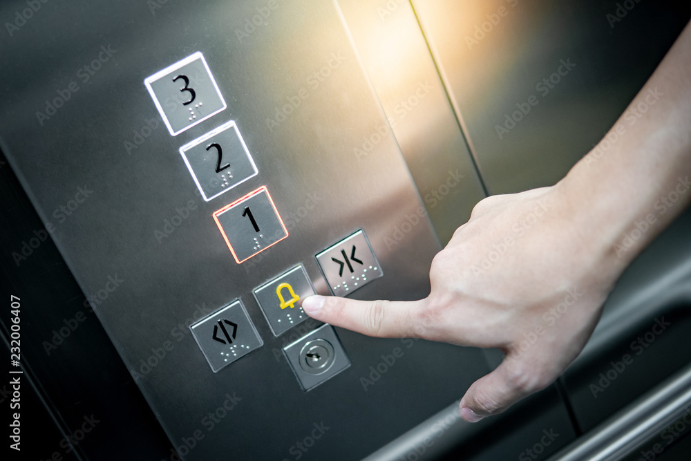 Male forefinger pressing on emergency stop and alarm button in elevator ...