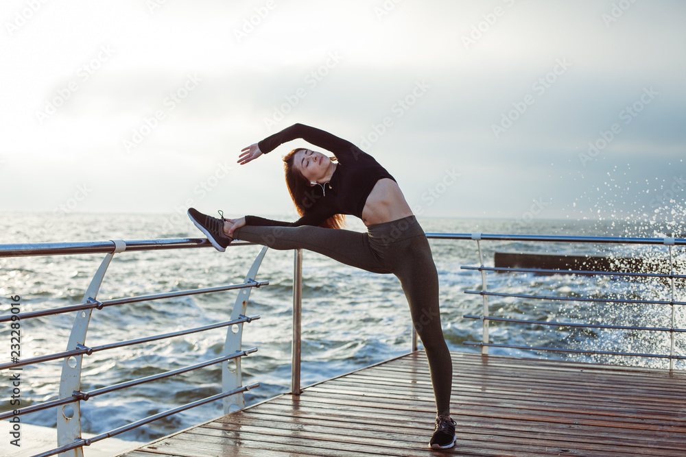 Fitness model athlete girl warm up stretching her hamstrings, leg and ...