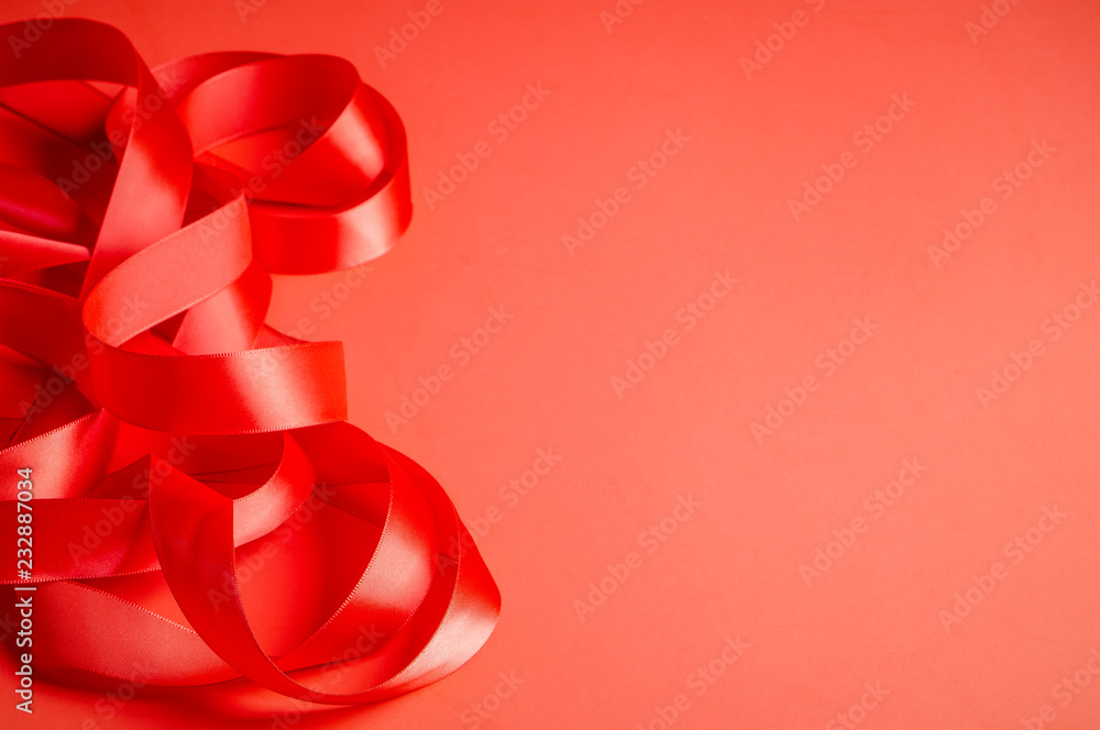An artistic and flowing swirl of medium-width shiny red satin ribbon ...