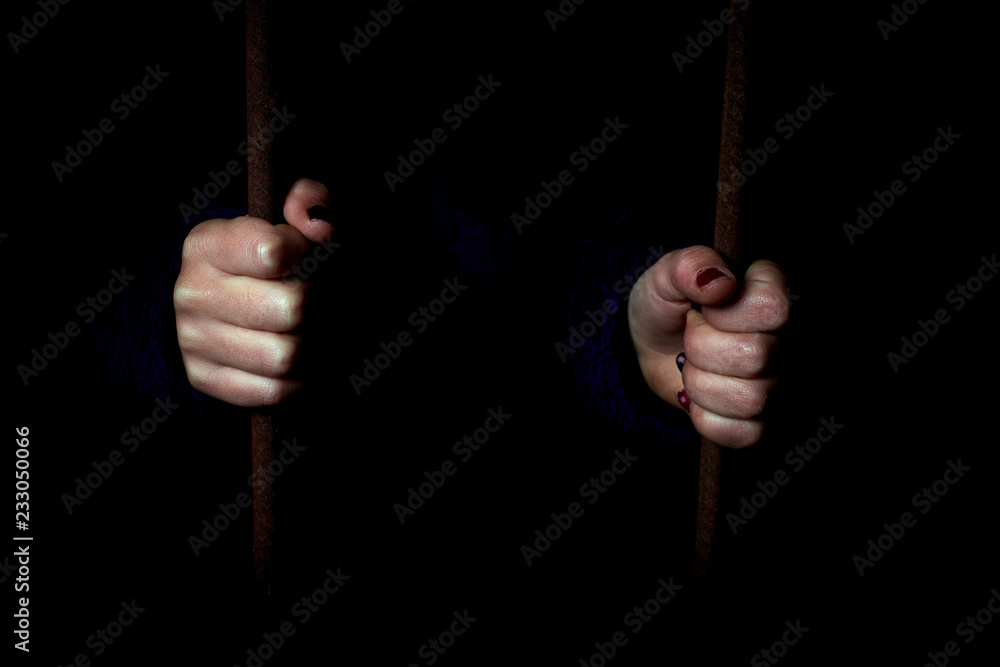 Child hands holding bars in a dark hiding place. Concept image of ...