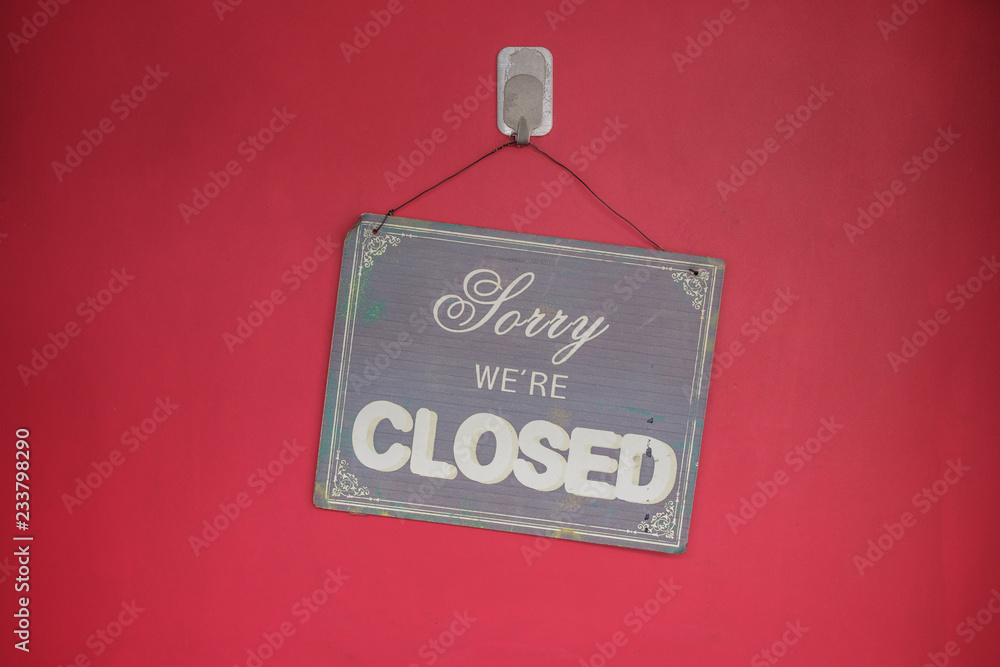 Aged fancy writing "Sorry we are closed " sign hanging crooked on a ...