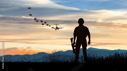 Silhouette of soldier at sunset watching the launch of paratroopers ...