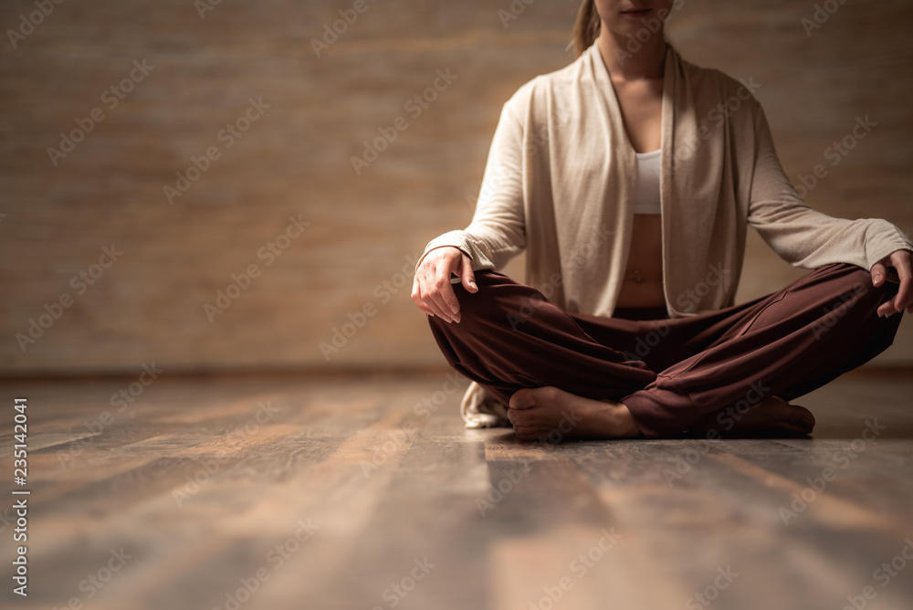 Calm young woman sitting on the floor with her legs crossed and ...