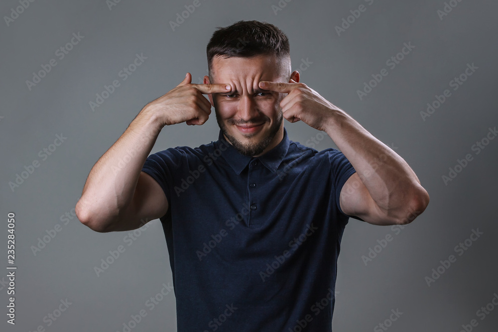 portrait of man grimacing,clenching eyebrows with fingers, changes the ...