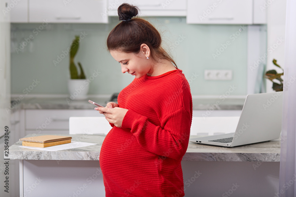 Sideways shot of brunette young woman types text message on cellular ...