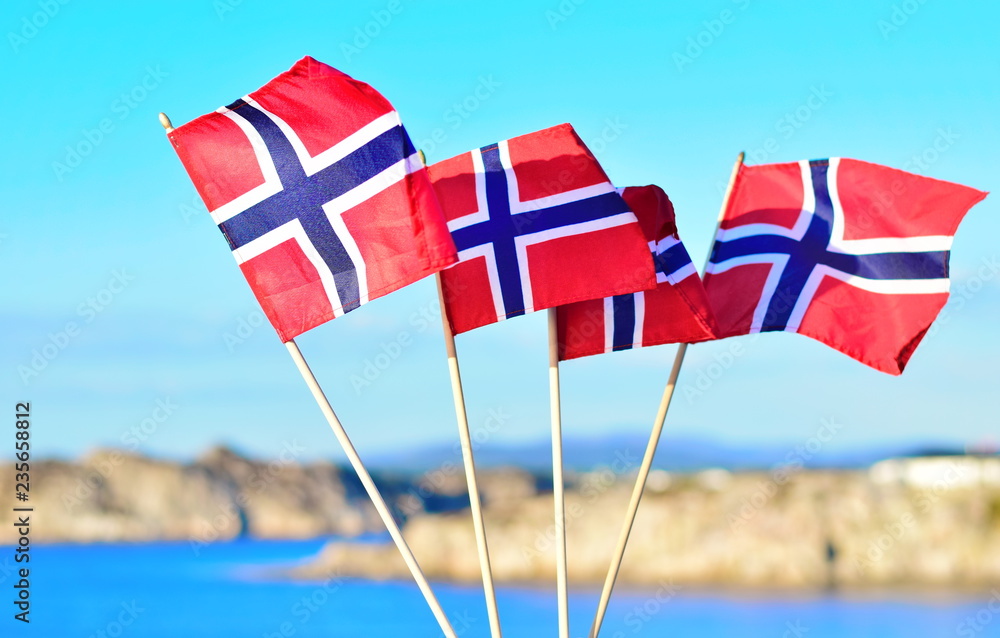 Four flags of Norway are fluttering in the wind against the blue sky ...