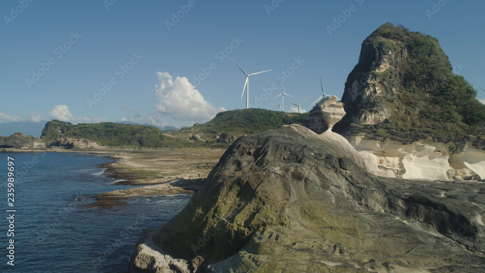 Natural rock formation of limestone stone on the coast with windmills ...