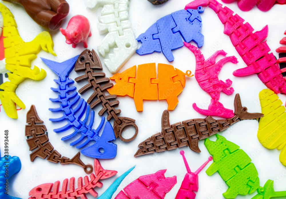 Many bright multi-colored objects printed on 3d printer lie on flat ...