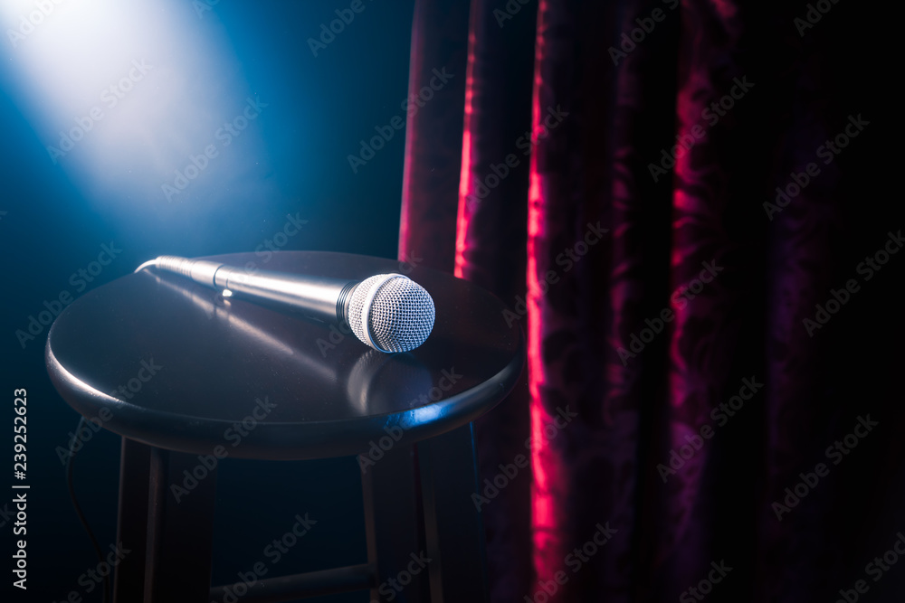 microphone on a wooden stool on a stand up comedy stage with reflectors ...