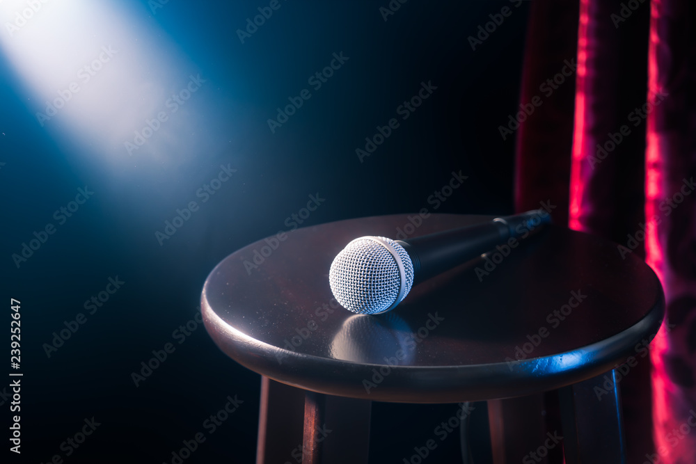 microphone on a wooden stool on a stand up comedy stage with reflectors ...