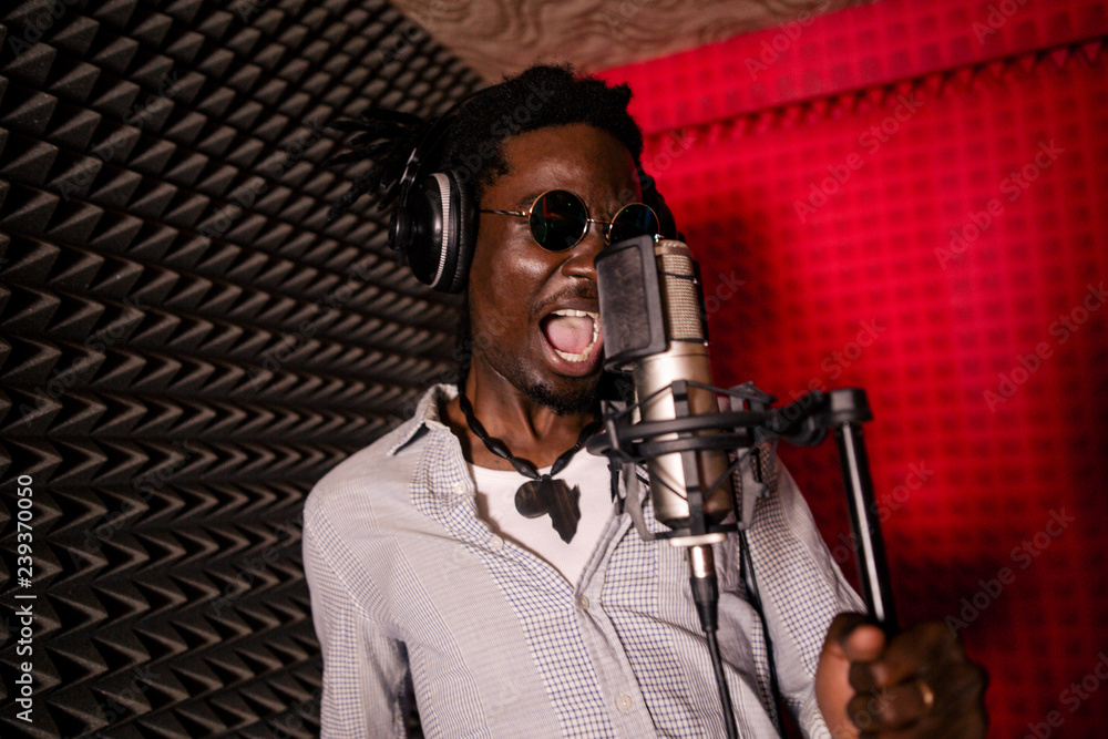 African man loudly singing a song in the recording Studio. Guy singer ...