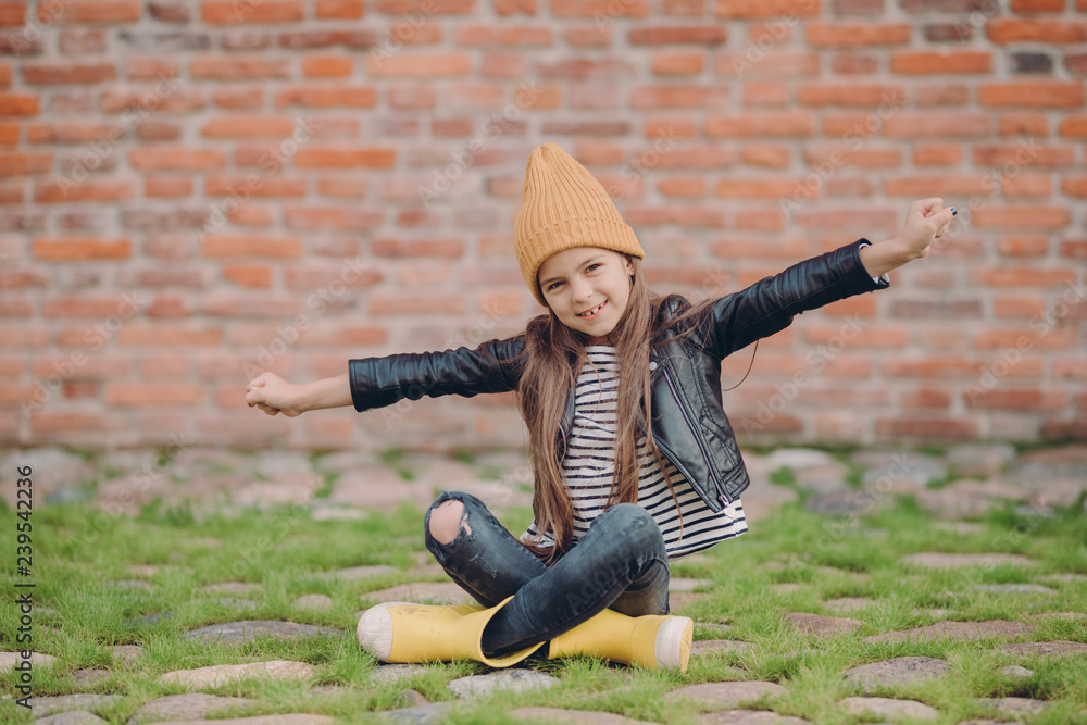 Beautiful little girl sits in lotus pose, stretches arms, wears yellow ...