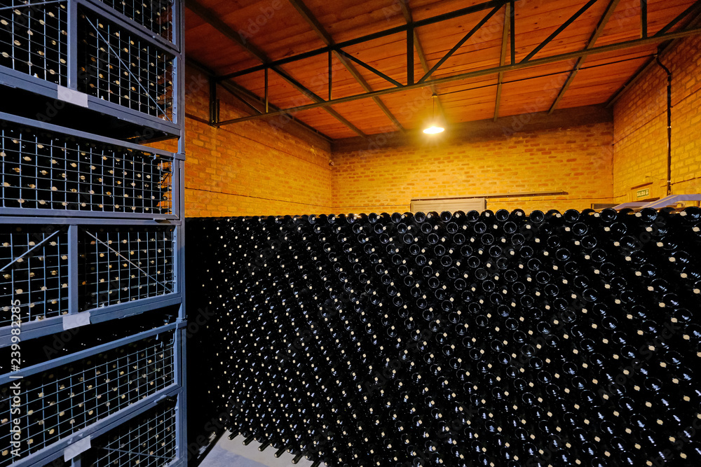 Resting wine bottles stacked in the cellar of a Malbec winery factory ...