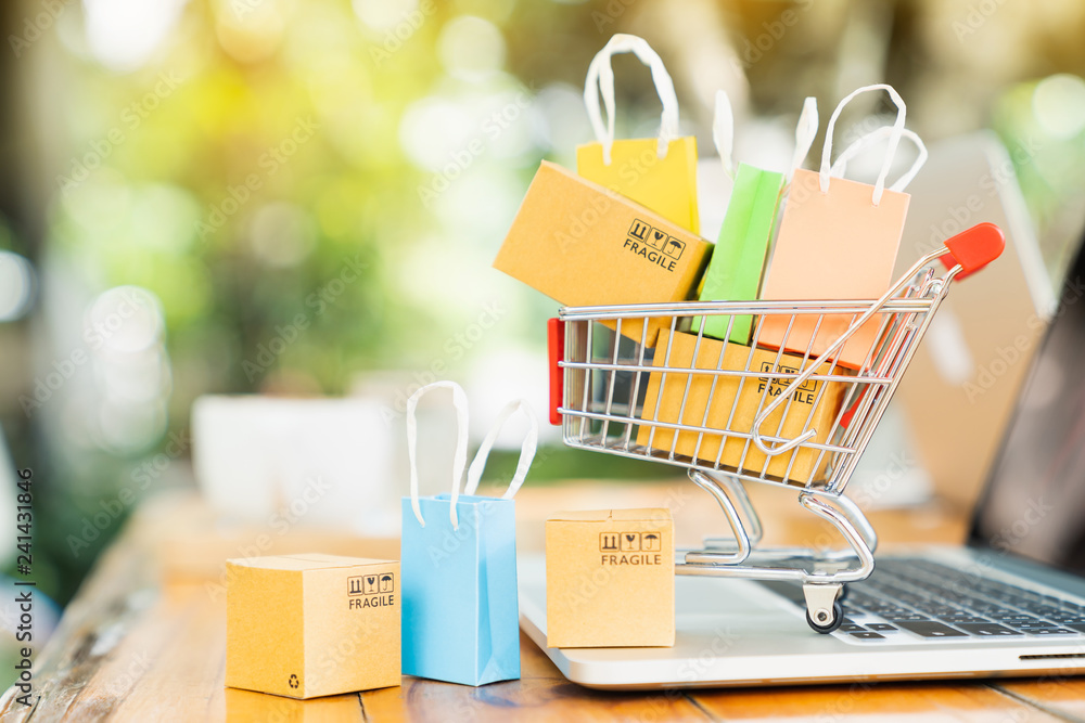 Product package boxes and shopping bag in cart with laptop computer ...