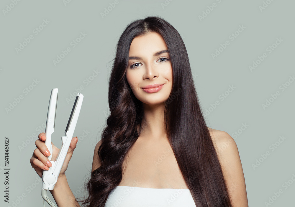 Happy woman with straight hair and curly hair using hair straightener ...
