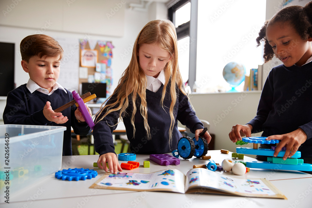 Three primary school children working together, following an ...