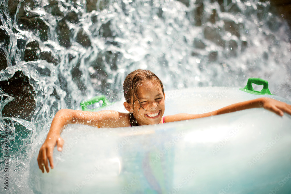 Laughing girl being splashed by water while floating in an inflatable ...
