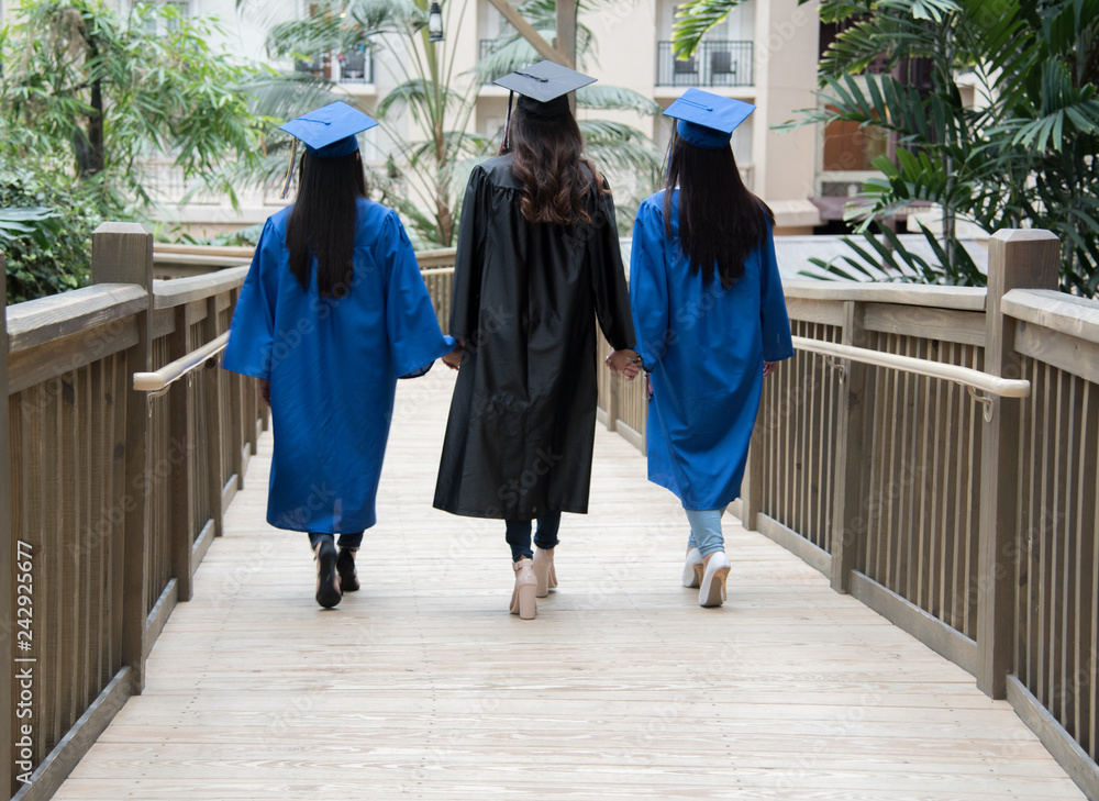 Foto de Stock Three girl friends graduate walking on bridge wearing ...