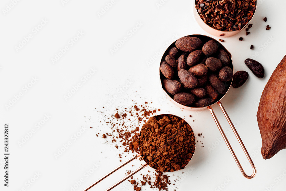 Rose gold measuring cups of cocoa beans, cacao nips, cocoa powder and ...