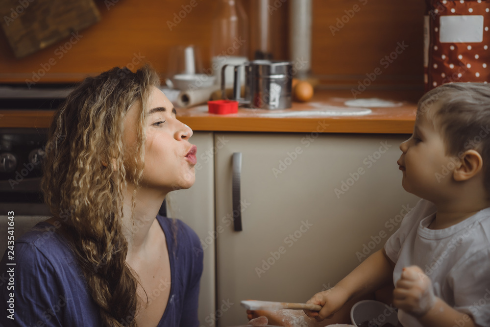 little boy in the kitchen helps mom to cook. the child is involved in ...