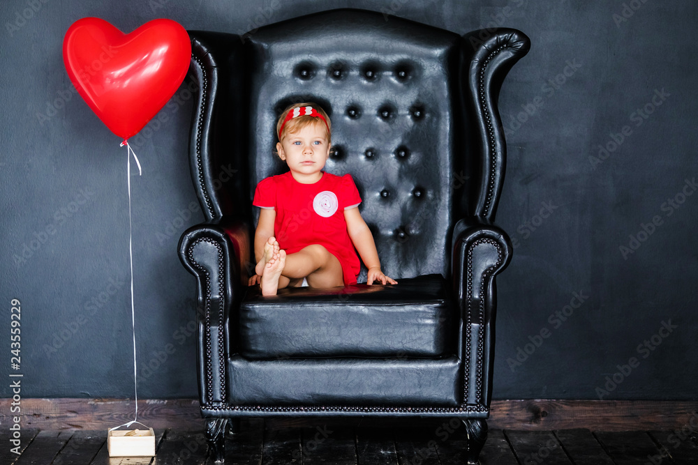 Little blonde girl in red dress with red wreath with hearts sitting on ...