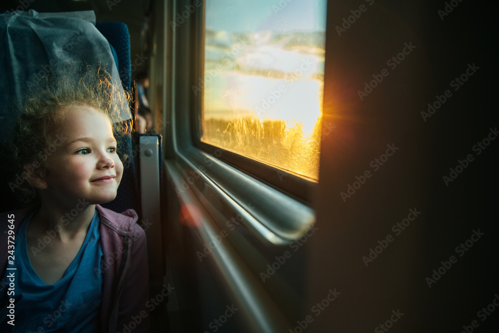 Beautiful little girl looking out train window outside, while it moving ...