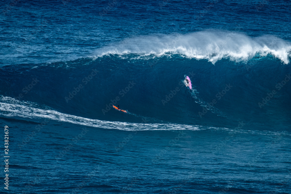 Two big wave surfers paddle to line up and pass huge ocean wave of Jaws (Peahi) surf spot on ...