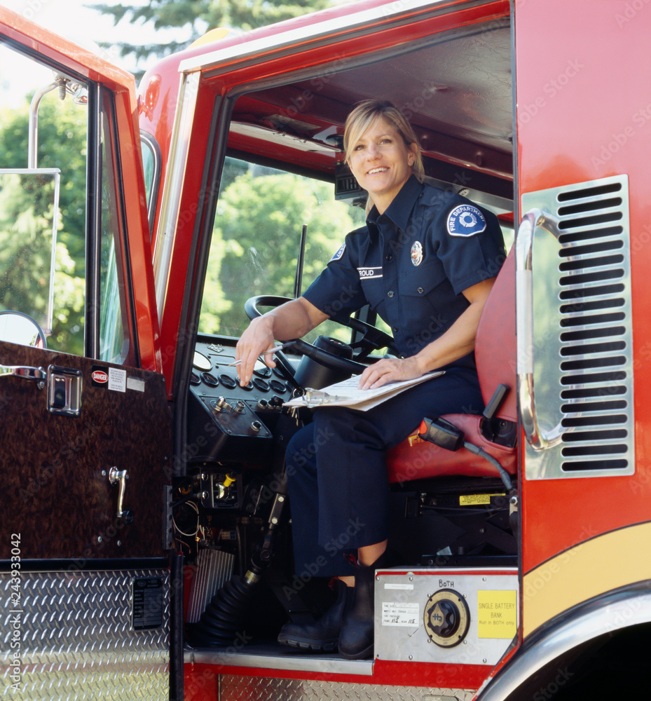 Smiling female woman firefighter sitting in driver's seat of fire ...