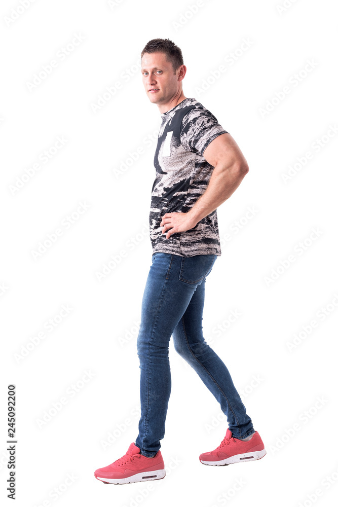Side view of handsome fit adult man walking with hands on hips. Full ...