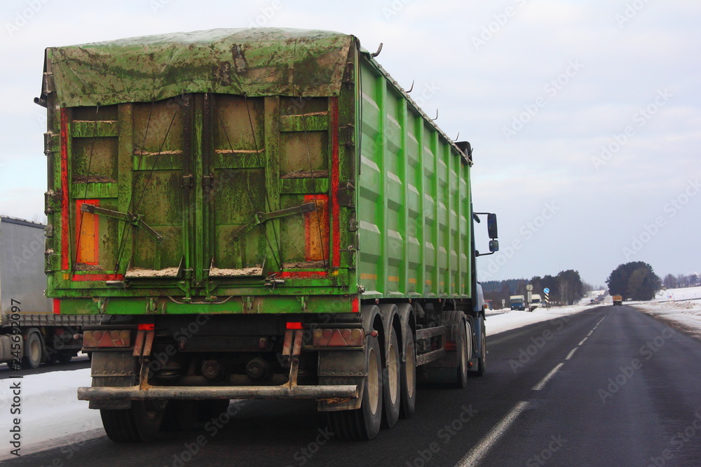 Heavy semi trailer truck with tented green open top container on winter ...