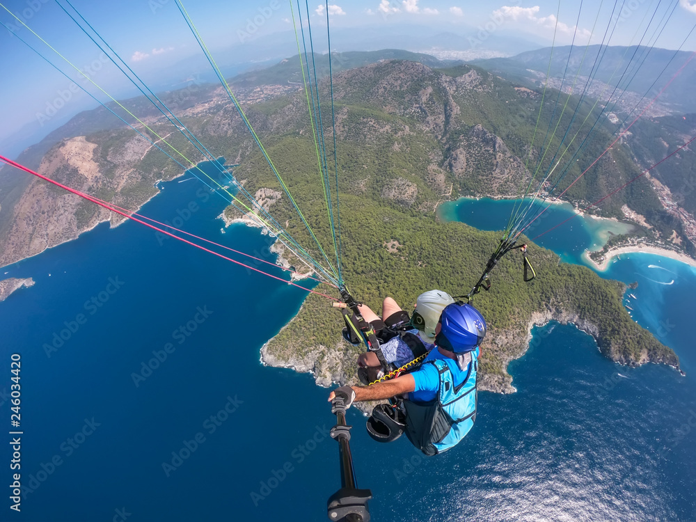 Paragliding in the sky. Paraglider tandem flying over the sea with blue ...