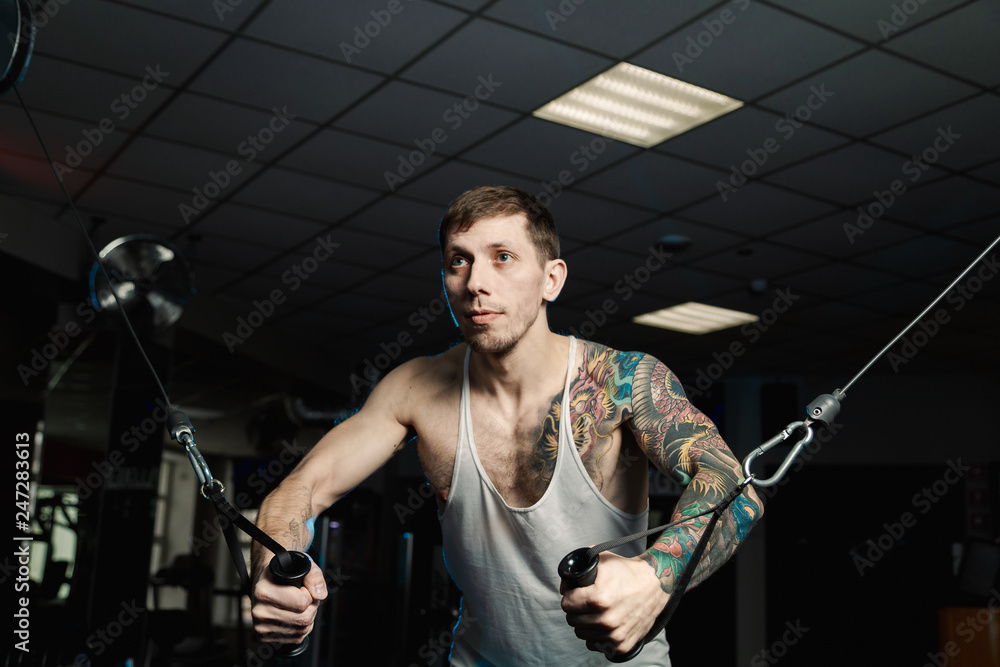 Handsome athletic man trains pectoral muscles on a block simulator in ...