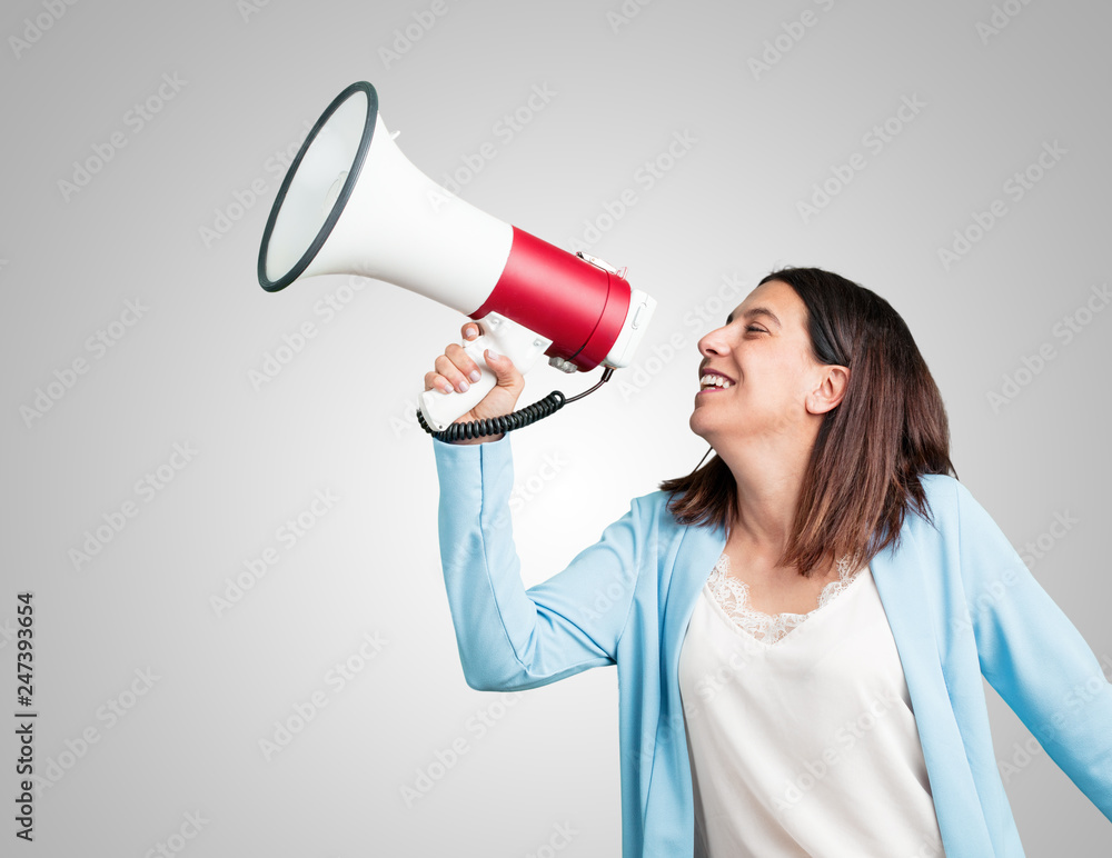 Middle aged woman excited and euphoric, shouting with a megaphone, sign ...
