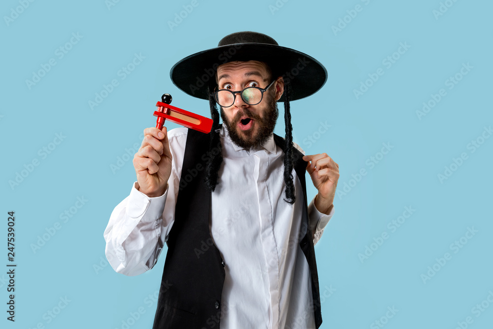 Portrait of a young orthodox Hasdim Jewish man with wooden Grager ...
