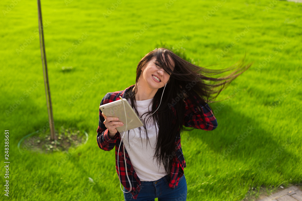 young brunette woman listen top chart song. Jump and dance on the grass ...