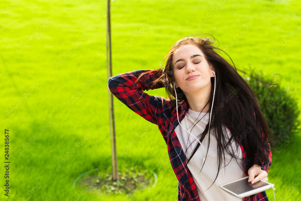 young brunette woman listen top chart song. Jump and dance on the grass ...