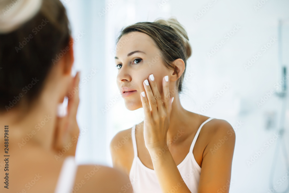 Woman applying face cream in bathroom Stock Photo | Adobe Stock