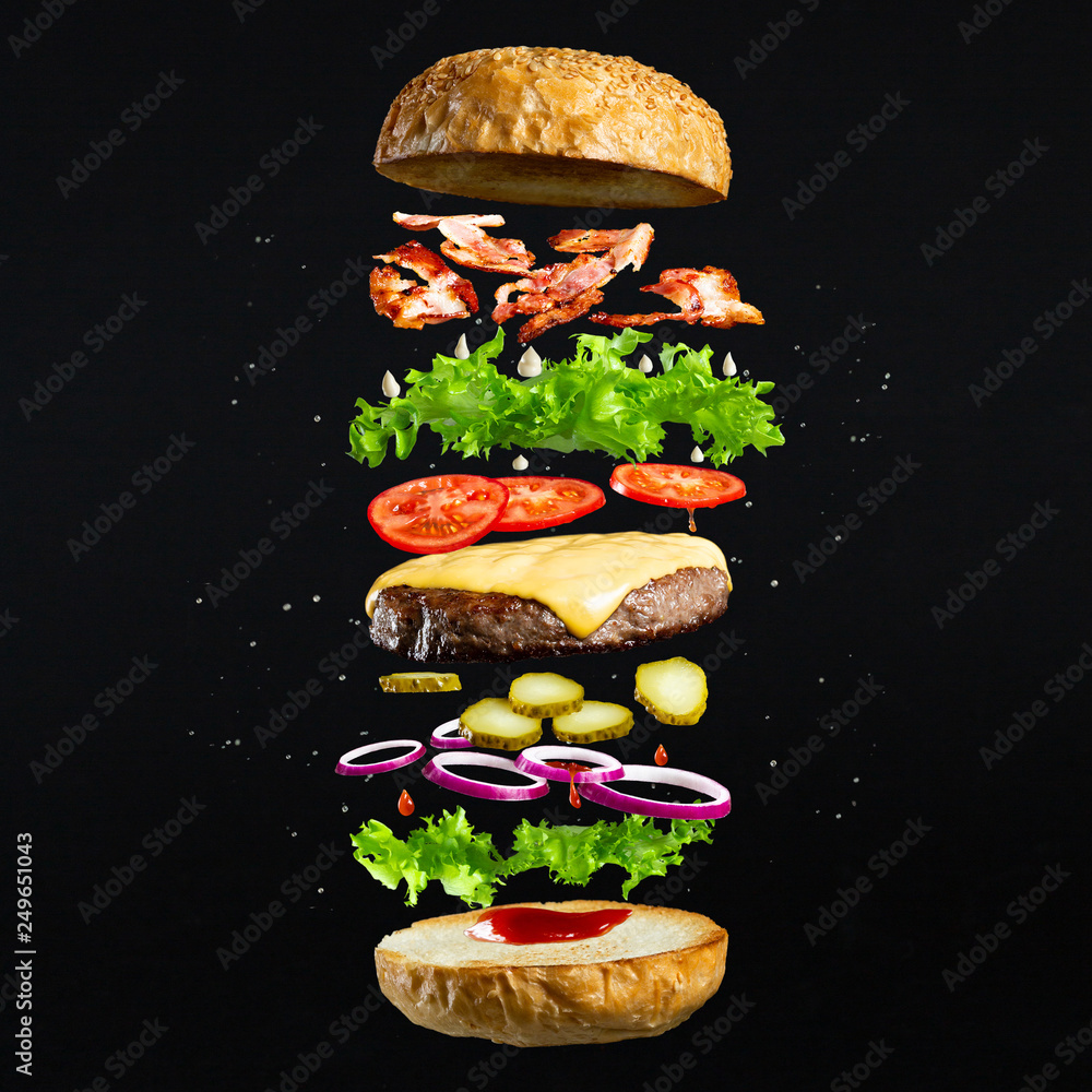 Floating burger isolated on black wooden background. Ingredients of a ...