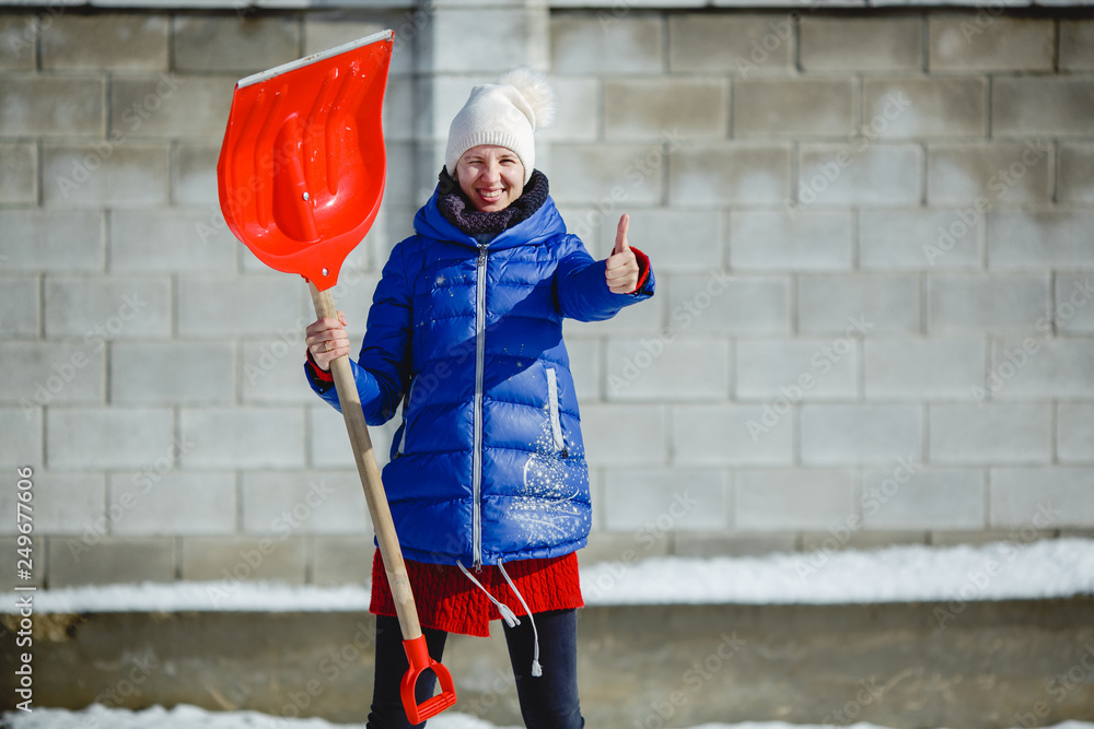 Happy girls with a snow shovel in the creek shows thumb up, snow ...