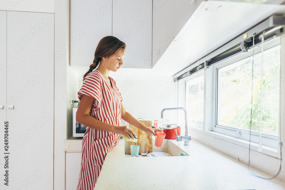 Teenage girl washing dishes in the kitchen Stock Photo | Adobe Stock