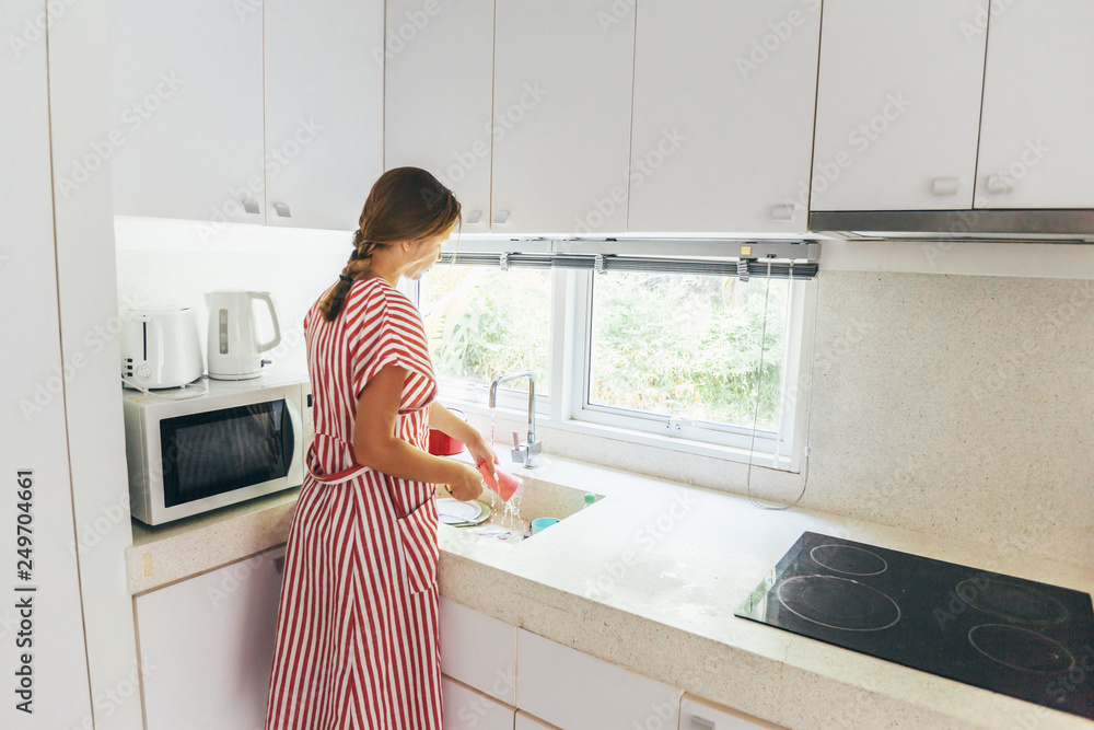 Teenage girl washing dishes in the kitchen Stock Photo | Adobe Stock