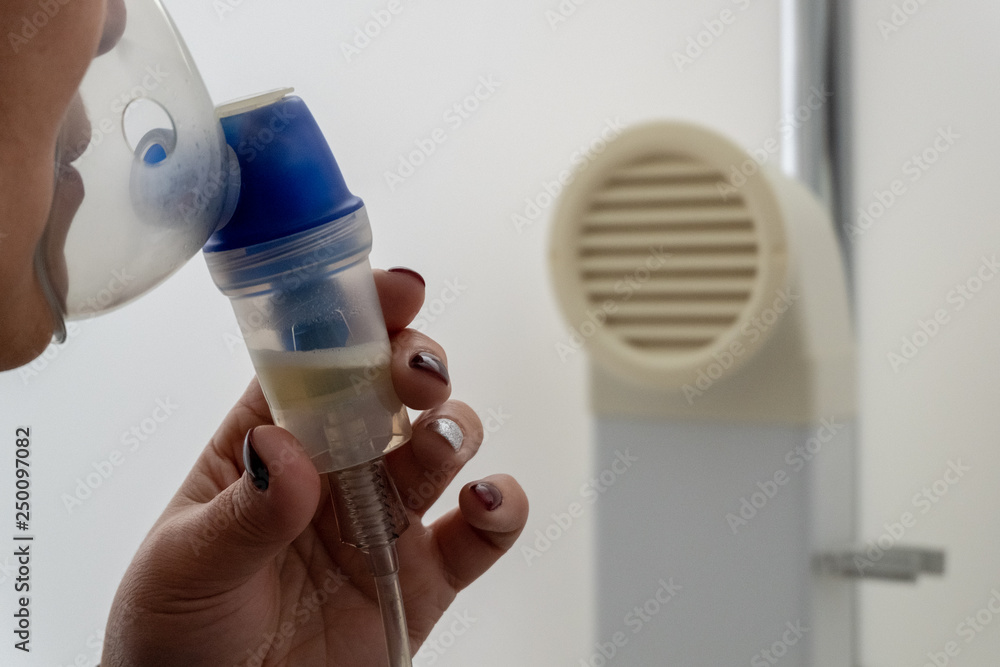 Inhalation procedure. A female hand holds an inhaler on face. A ...