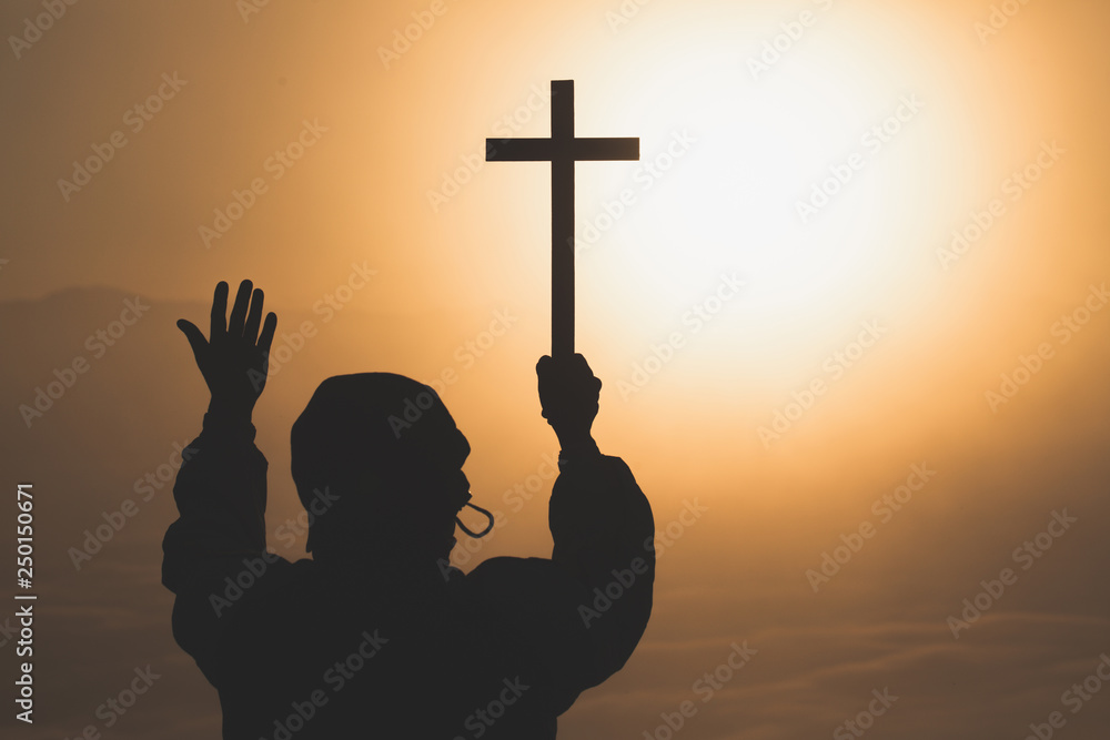 Silhouette the cross in hands, religion symbol in light and landscape ...