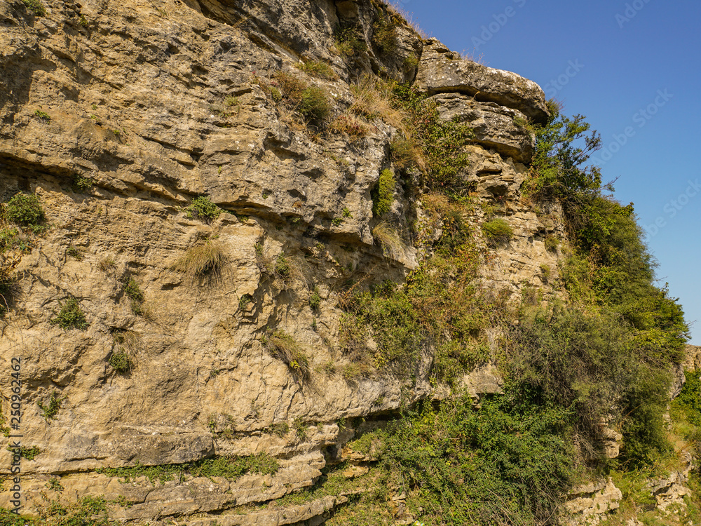 Bottom view of the steep cliff rocks Tarki-tau. Grass on the eastern ...