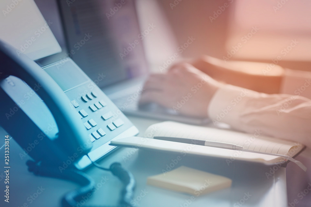 Male hand, IP phone with buttons and big display, laptop on the office ...