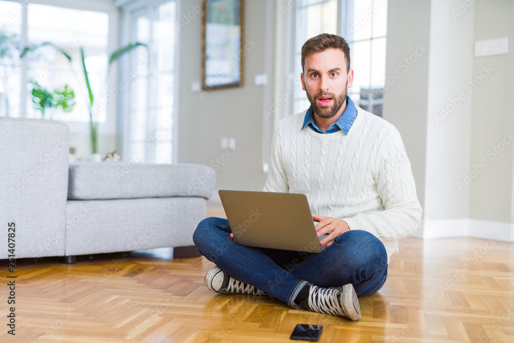 Handsome man wearing working using computer laptop afraid and shocked ...